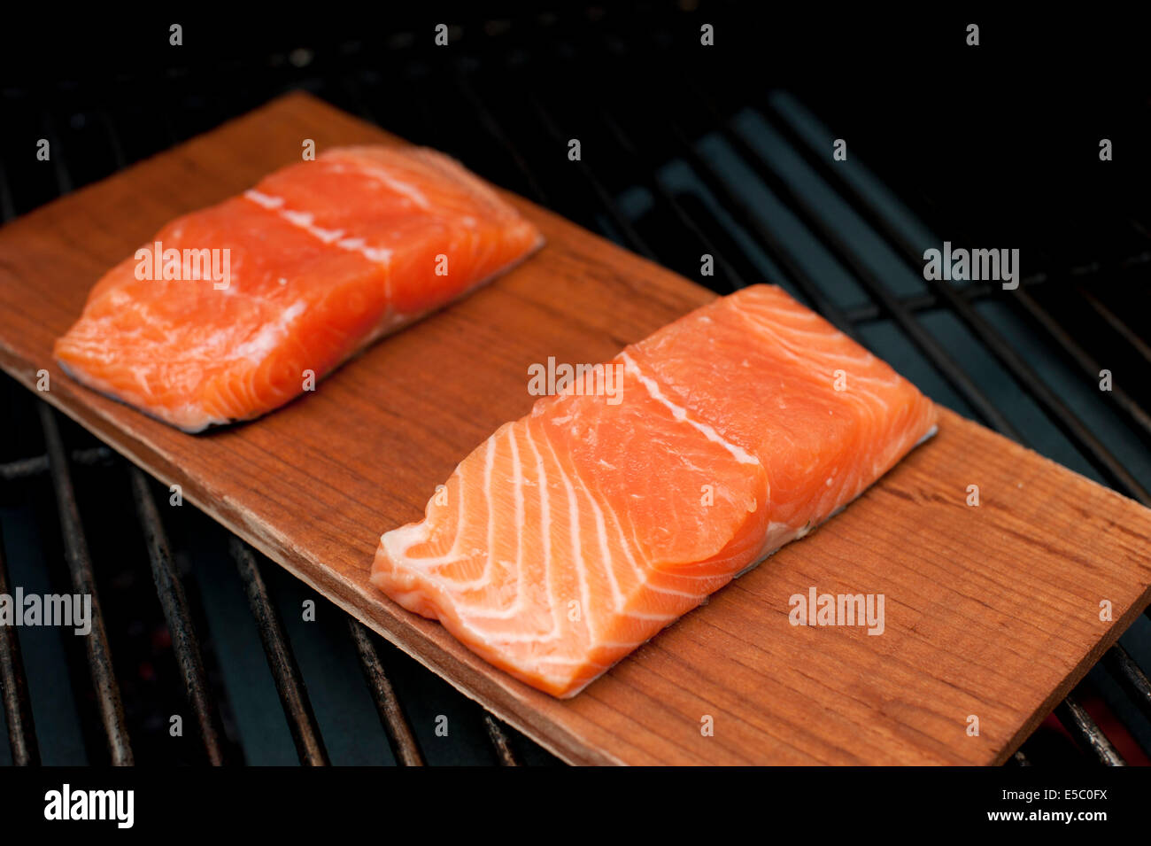 A pair of raw wild Alaskan Salmon fillets on a cedar plank being ...