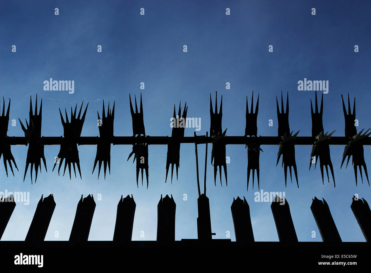 Imposing spiky metal fence silhouette from low angle and blue sky Stock ...