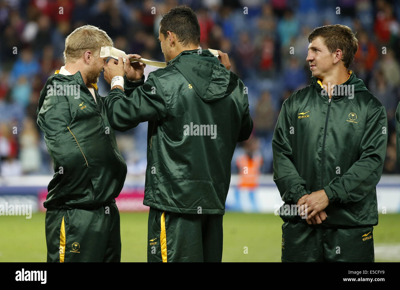 Glasgow, UK. 27th July, 2014. Chris Dry (C) of South Africa helps take ...