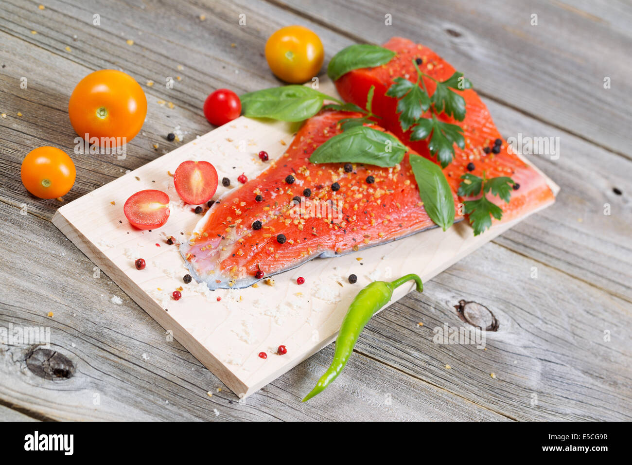 Angled horizontal view of raw red salmon, skin side down, on maple wood ...