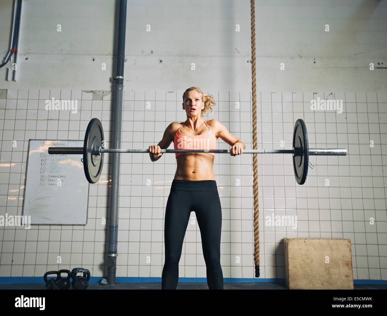 Young strong woman practices cross fit in a gym. Fit female holding a ...