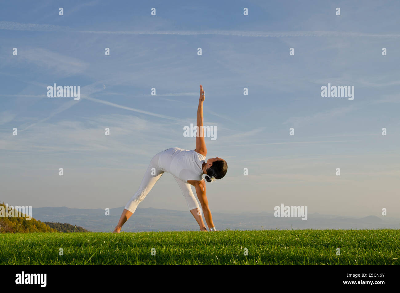 Young woman practising Hatha yoga, here the pose parivritta trikonasana ...