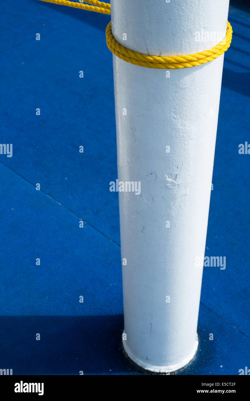 White painted steel pole with yellow rope against bright blue painted ...