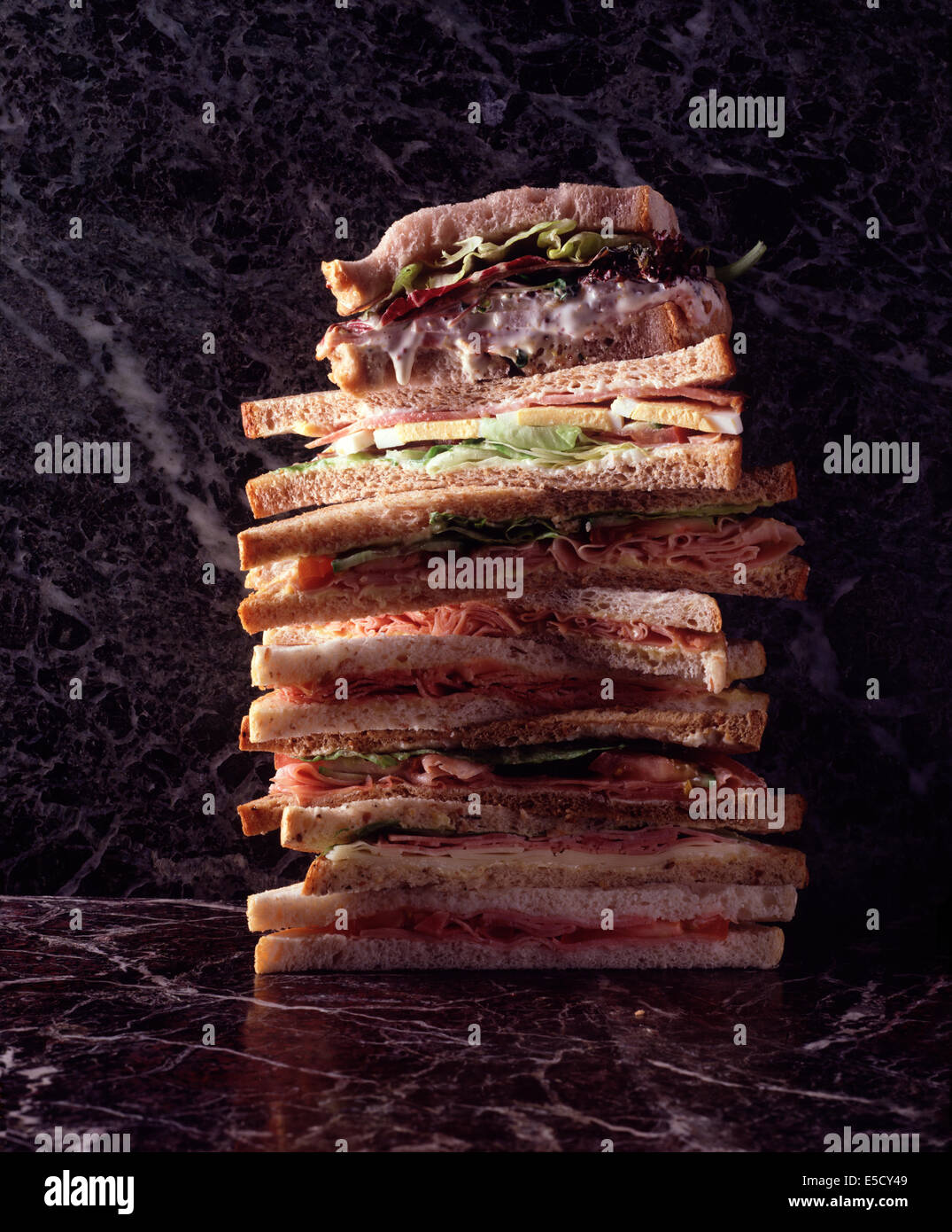 A stack of sandwiches one on top of the other, against a green and ...