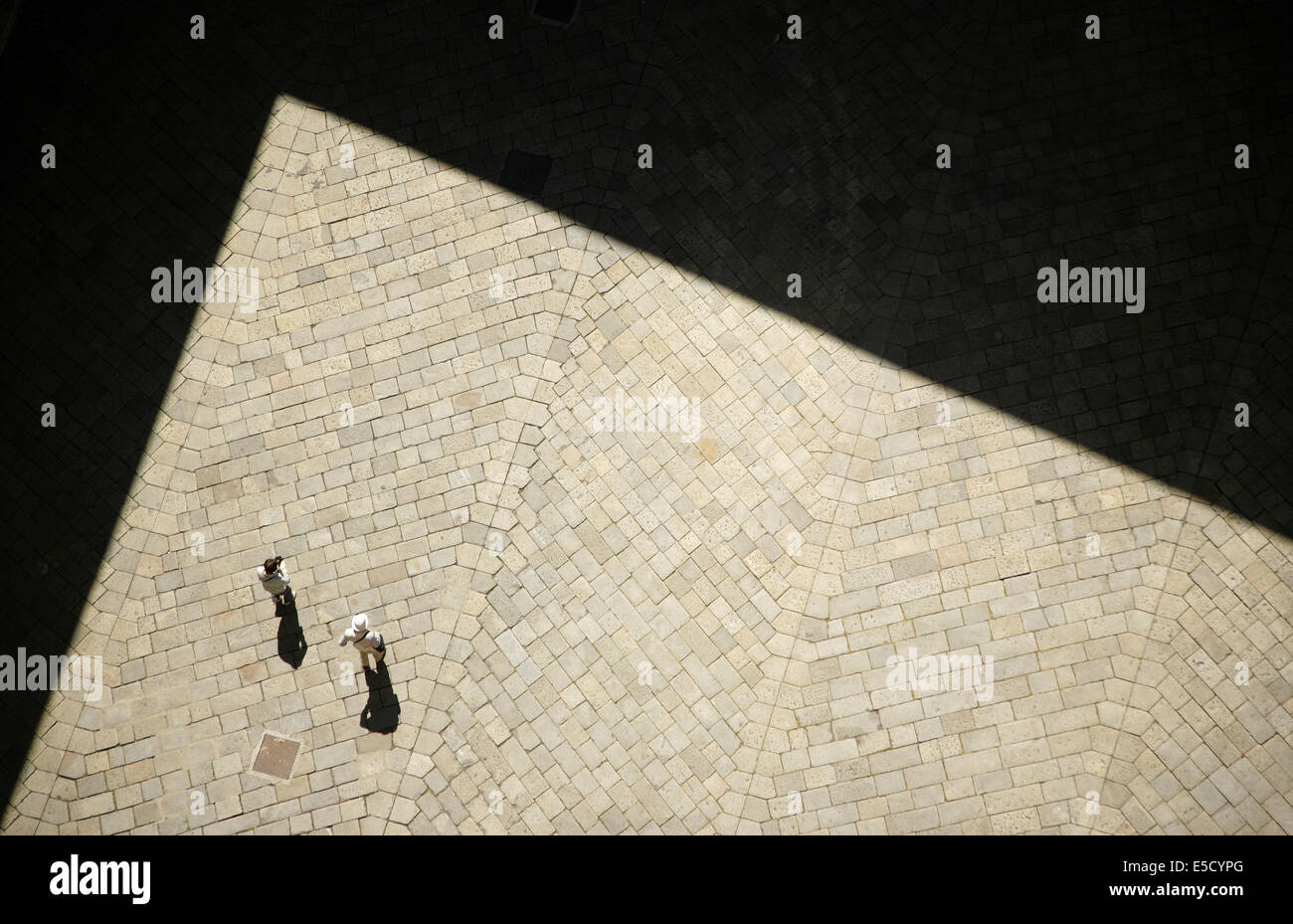 Two people walking across paved square Stock Photo - Alamy