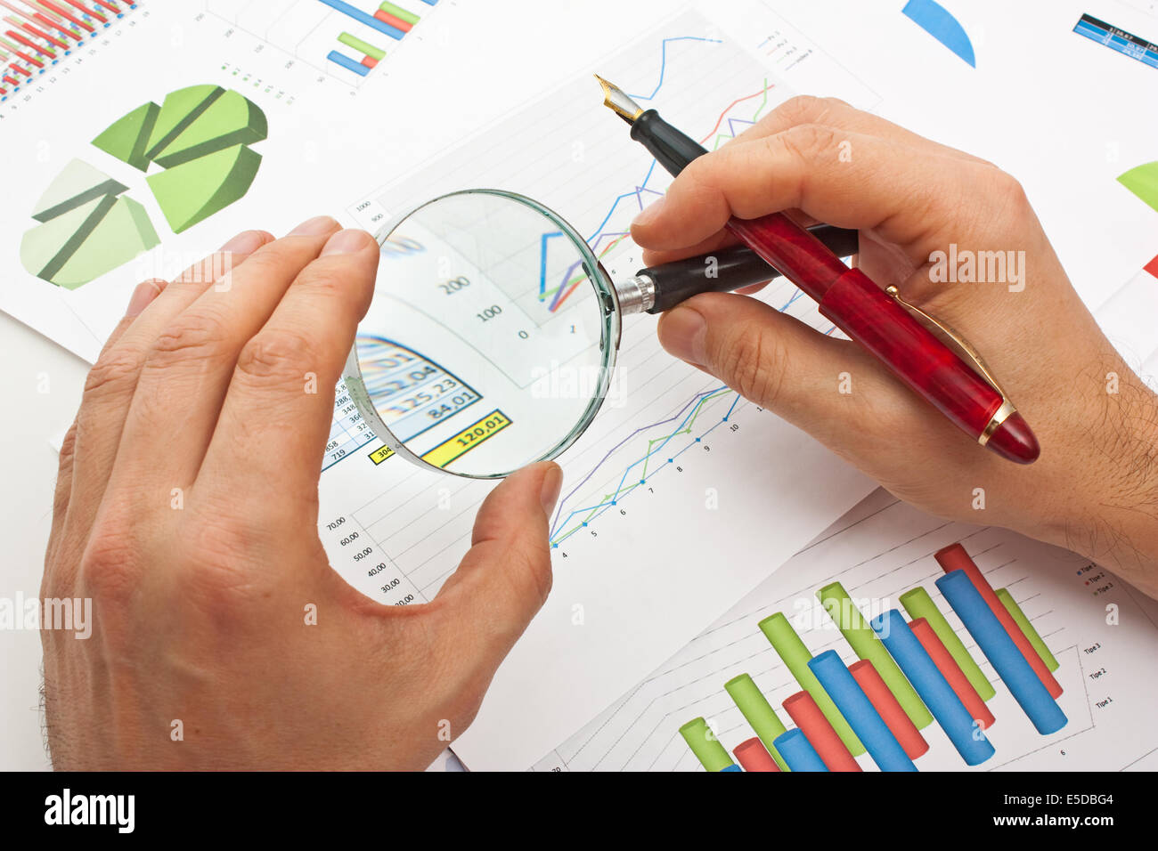 magnifying glass in hand and working paper chart Stock Photo - Alamy