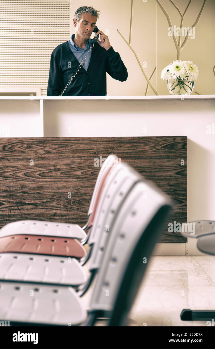 Male receptionist answering call in hospital waiting room Stock Photo ...