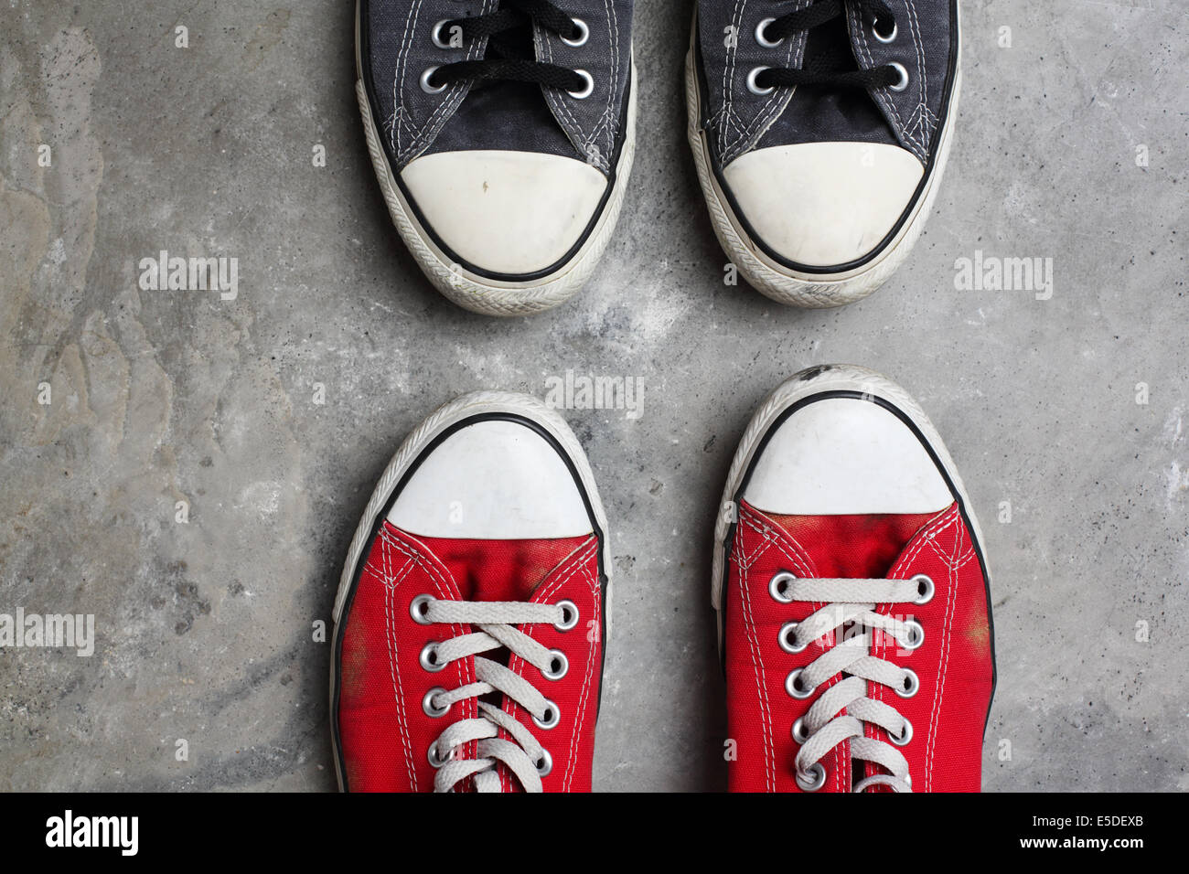 Two pairs of Converse shoes, toe to toe, shot against a concrete ...