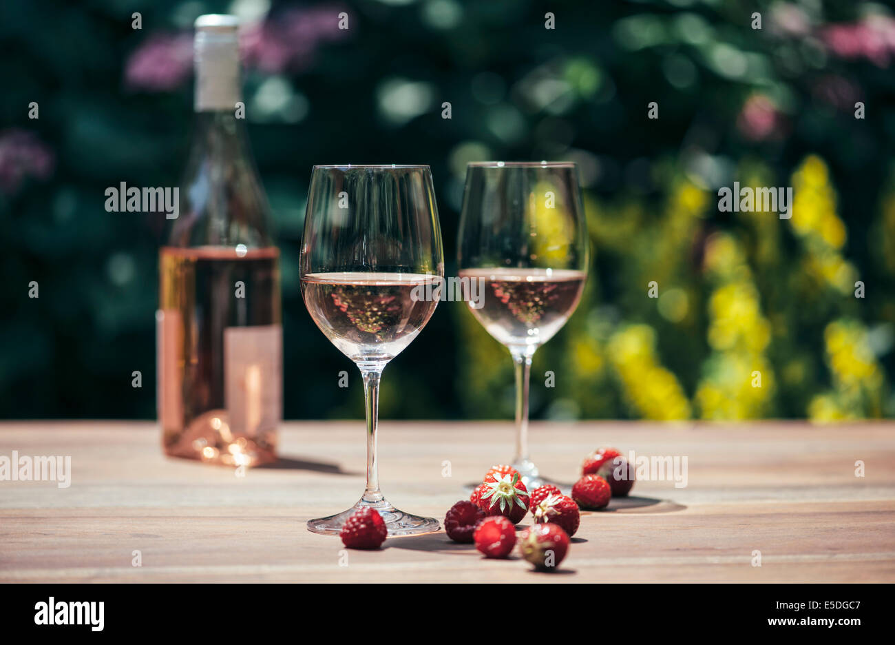 Two glasses of rose wine, wine bottle, strawberries and raspberries on ...