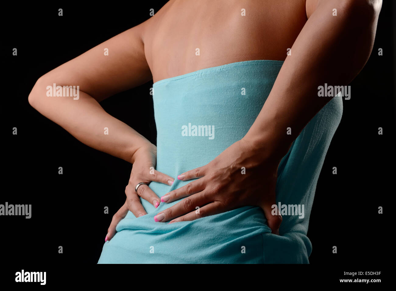 Young woman with back pain in front of black background, partial view ...