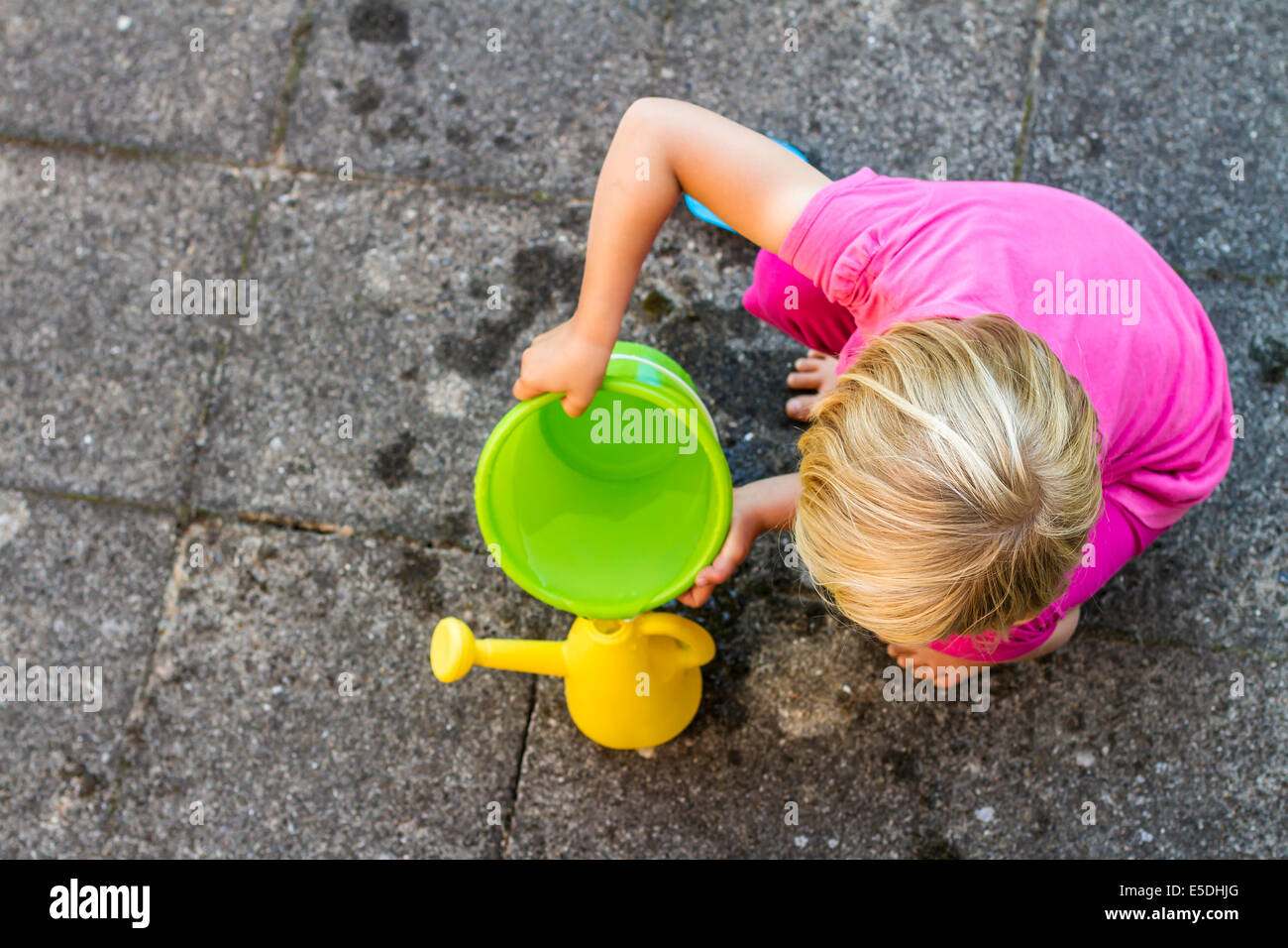 Little girl playing with water can and bucket Stock Photo - Alamy