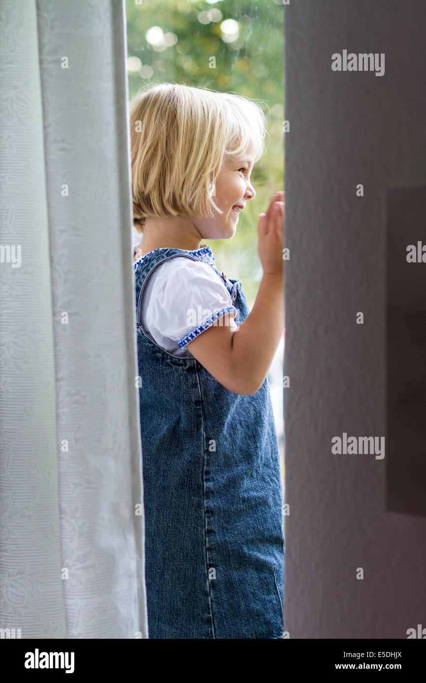 Portrait of little girl standing at the window Stock Photo - Alamy