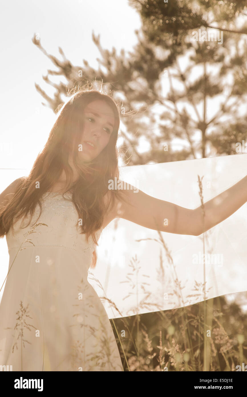 Portrait of teenage girl wearing white dress standing on meadow at ...