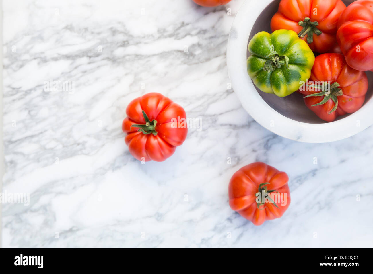 Marinda tomatoes in bol on marble plate Stock Photo - Alamy