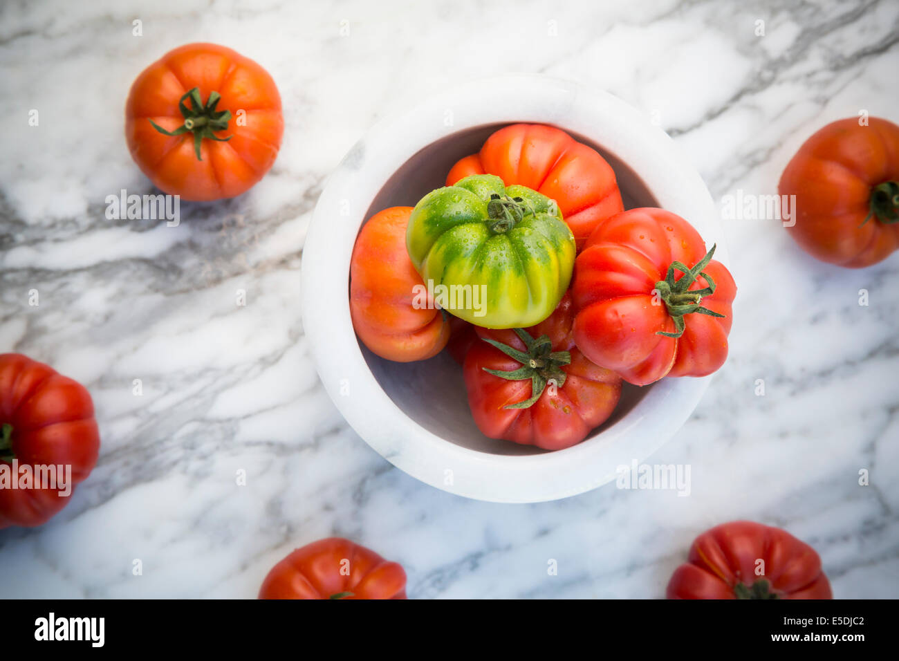 Marinda tomatoes in bol on marble plate Stock Photo - Alamy