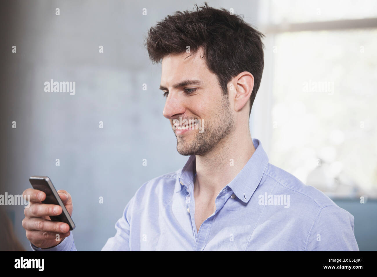 Portrait of smiling man looking at his smartphone Stock Photo - Alamy