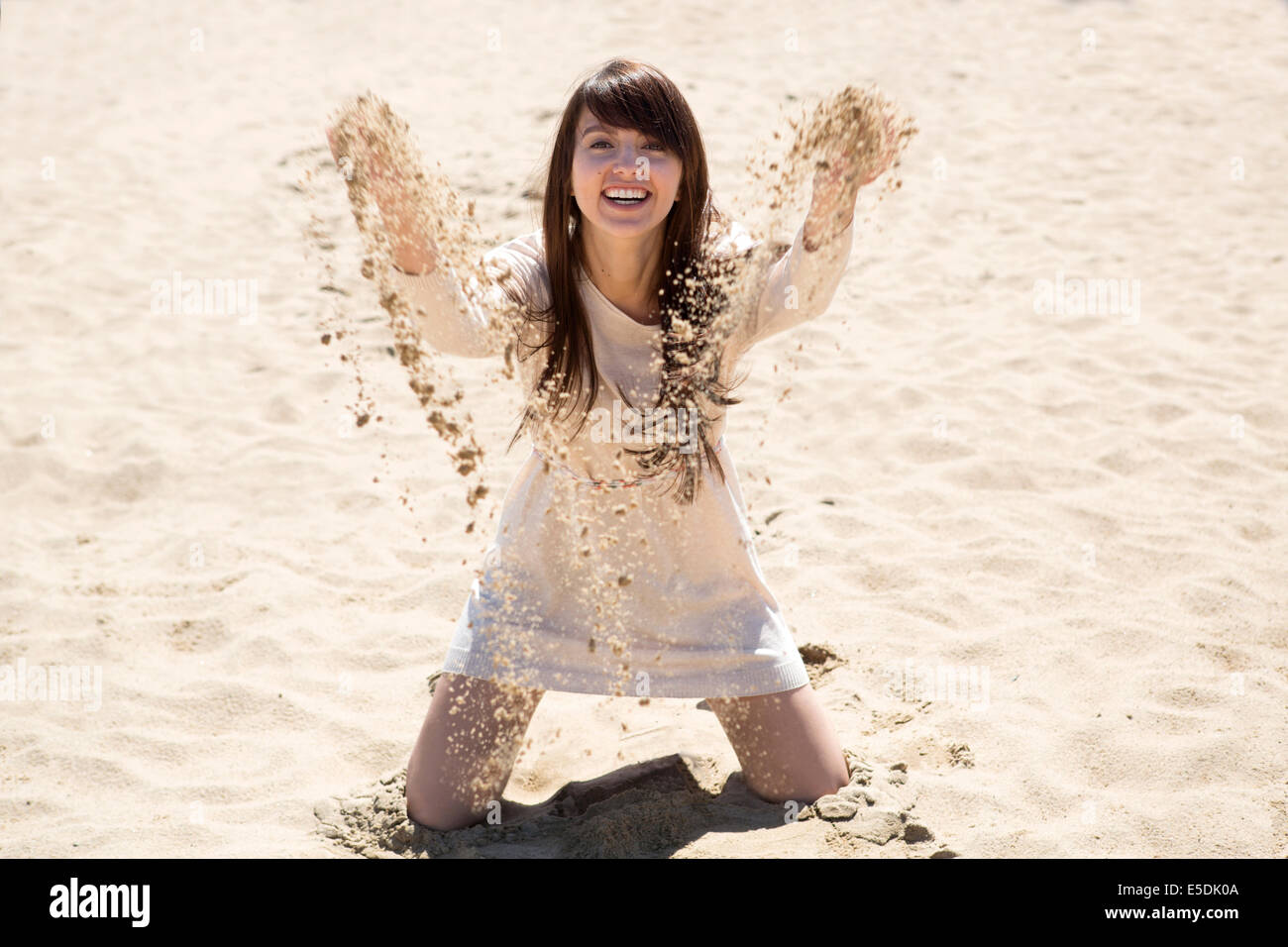 Portrait of smiling young woman throwing with sand Stock Photo - Alamy