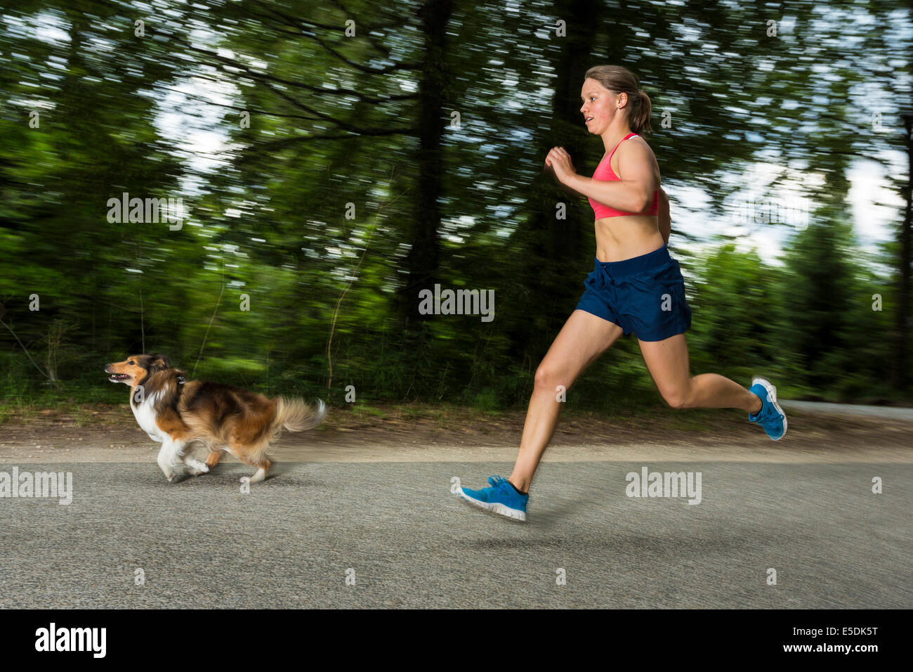 Young woman jogging with dog on road Stock Photo - Alamy
