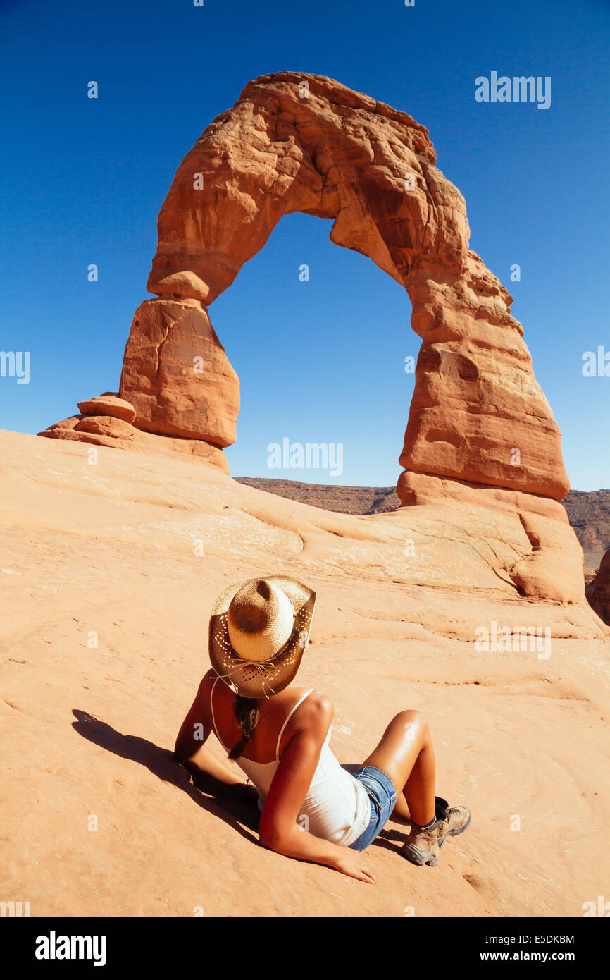 USA, Utah, woman relaxing in front of Delicate Arch at Arches National ...