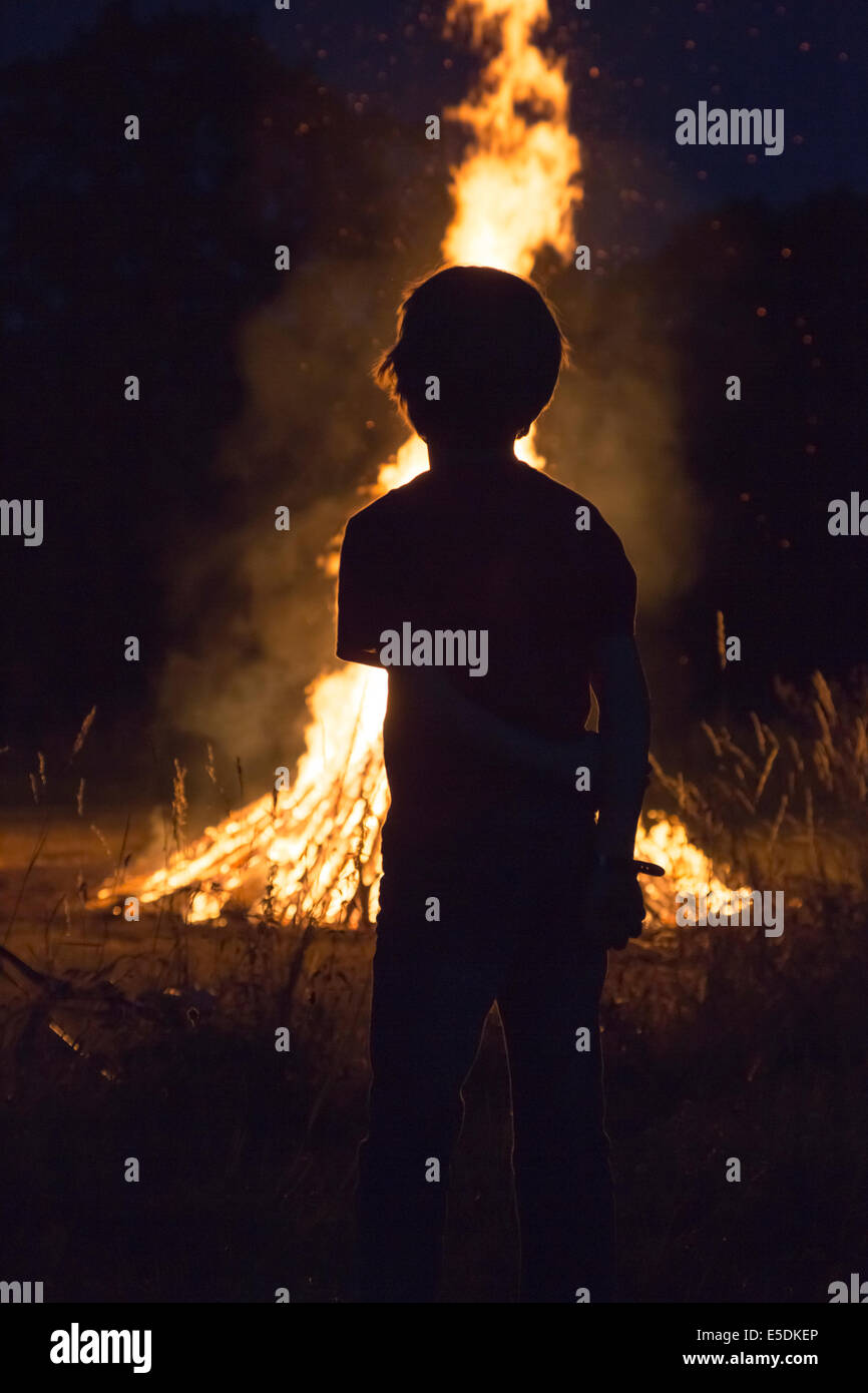 Boy standing in front camp fire at solstice Stock Photo - Alamy