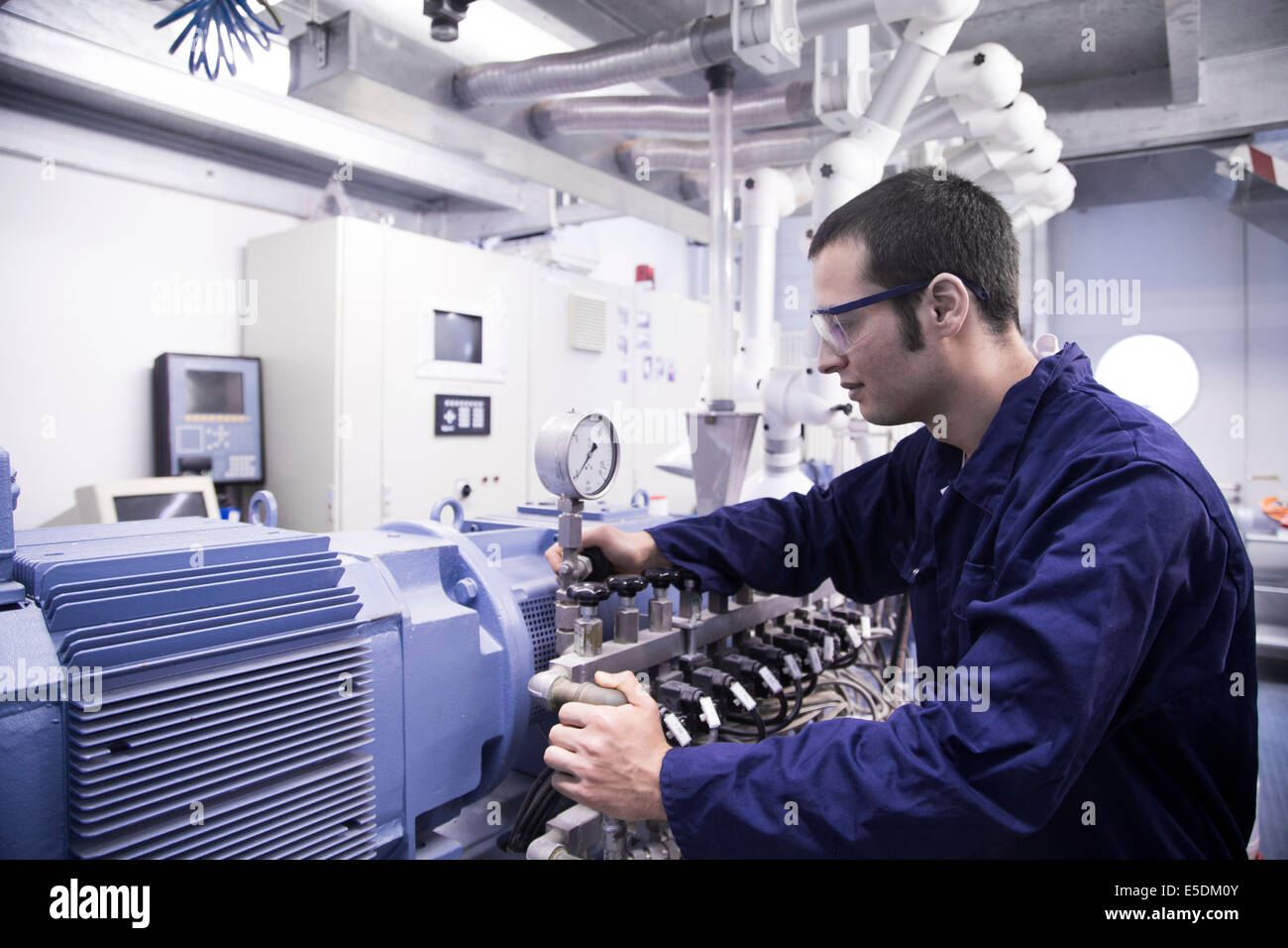 Technician working in a technical room looking at gauge Stock Photo - Alamy