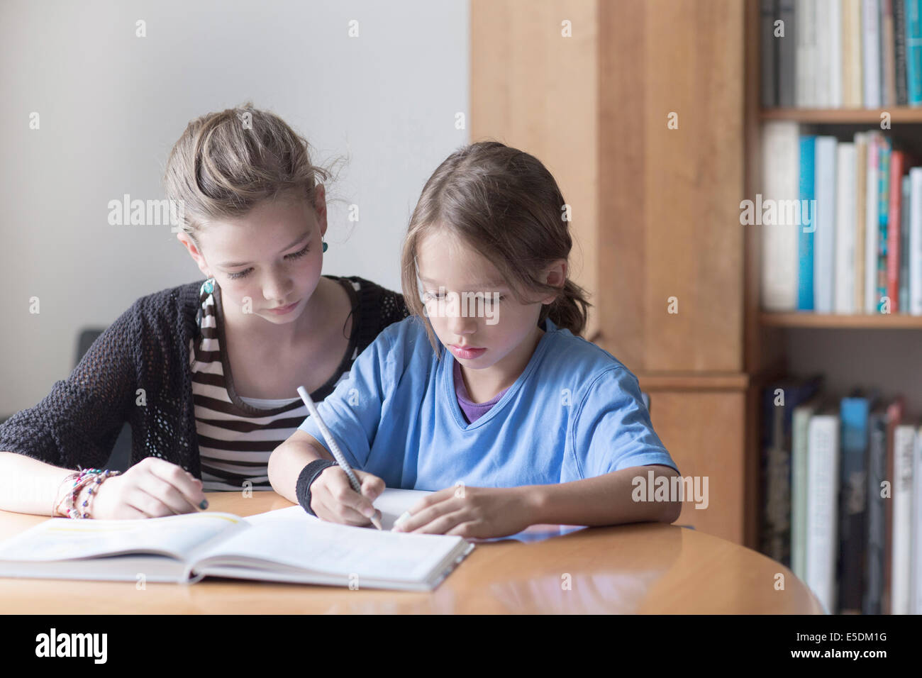 Sister helping her little brother by doing his homework Stock Photo - Alamy