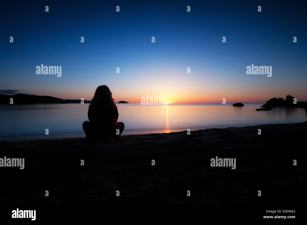 Spain, Menorca, Woman watching sunset at Playa de Cavalleria Stock ...