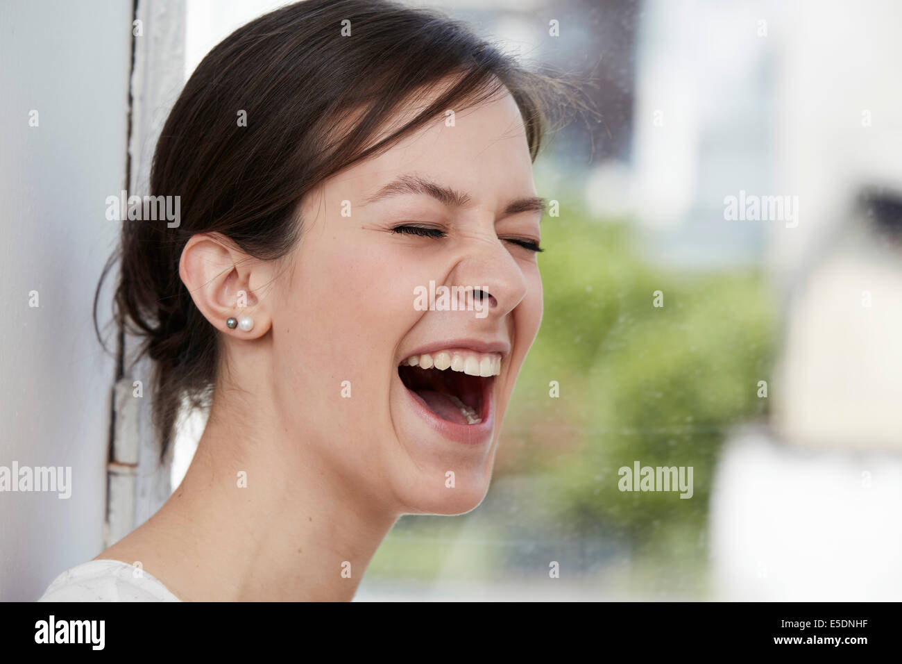 Laughing young woman at the window Stock Photo - Alamy