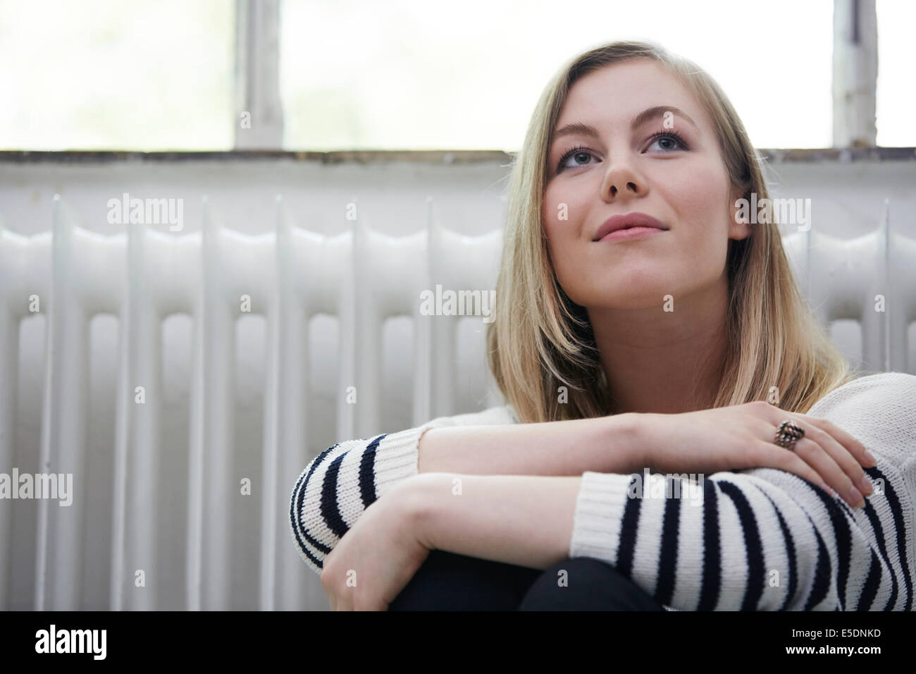 Young woman sitting at radiator Stock Photo - Alamy