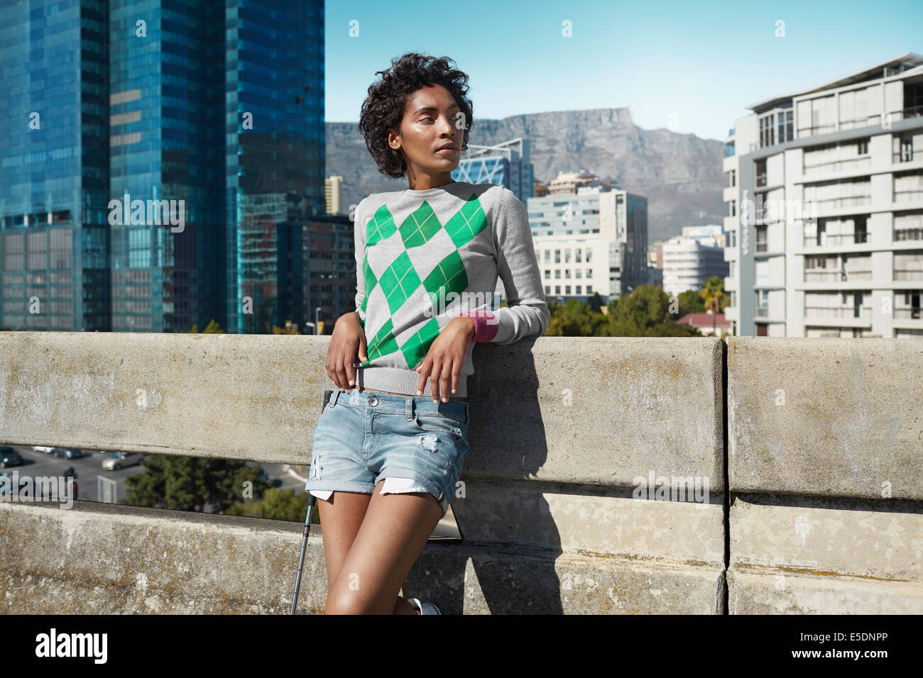 Young woman leaning against concrete railing in the city Stock Photo ...