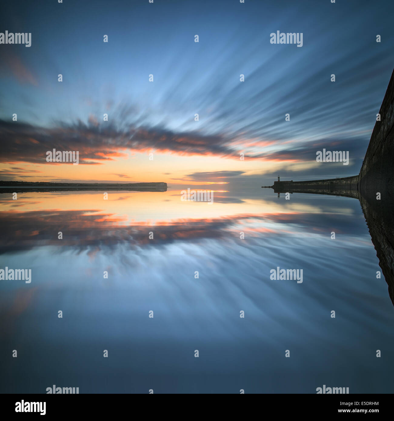 Stunning sunrise over ocean with lighthouse and harbor wall Stock Photo ...