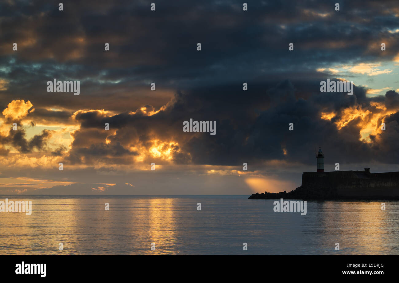 Stunning sunrise over ocean with lighthouse and harbor wall Stock Photo ...