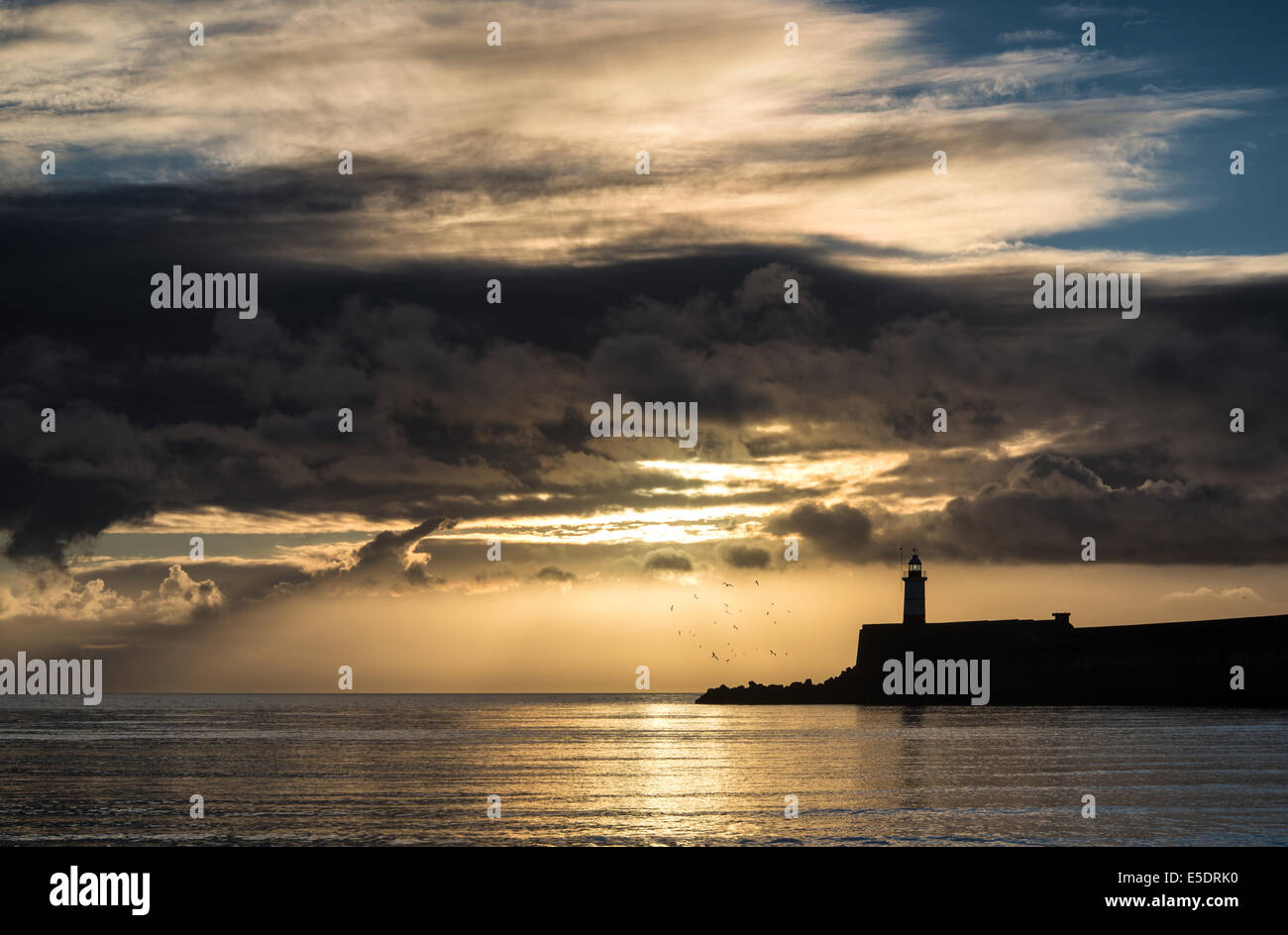 Stunning sunrise over ocean with lighthouse and harbor wall Stock Photo ...