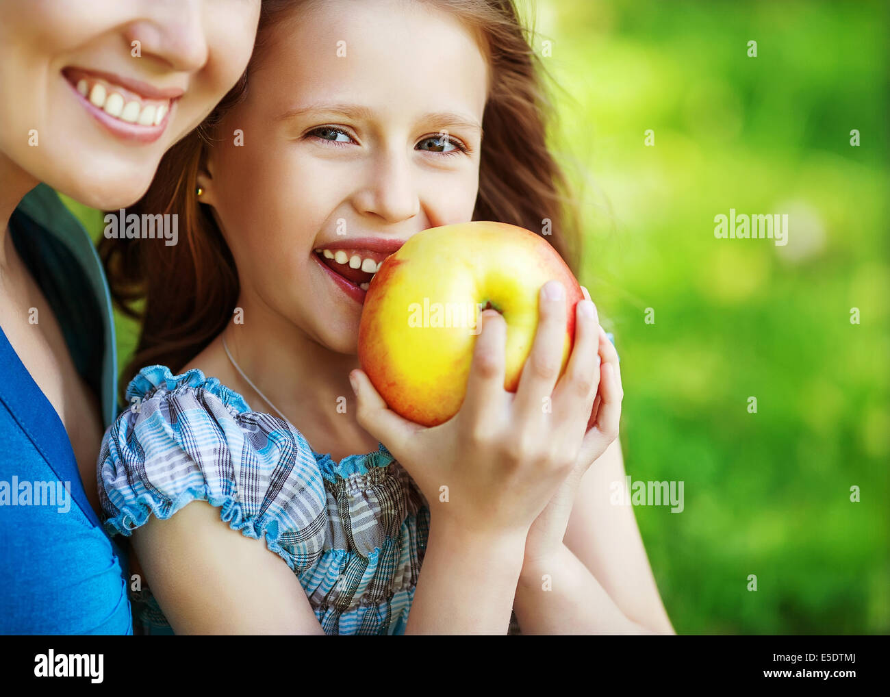 Mother and her child enjoy the early spring, eating apple, happy Stock ...