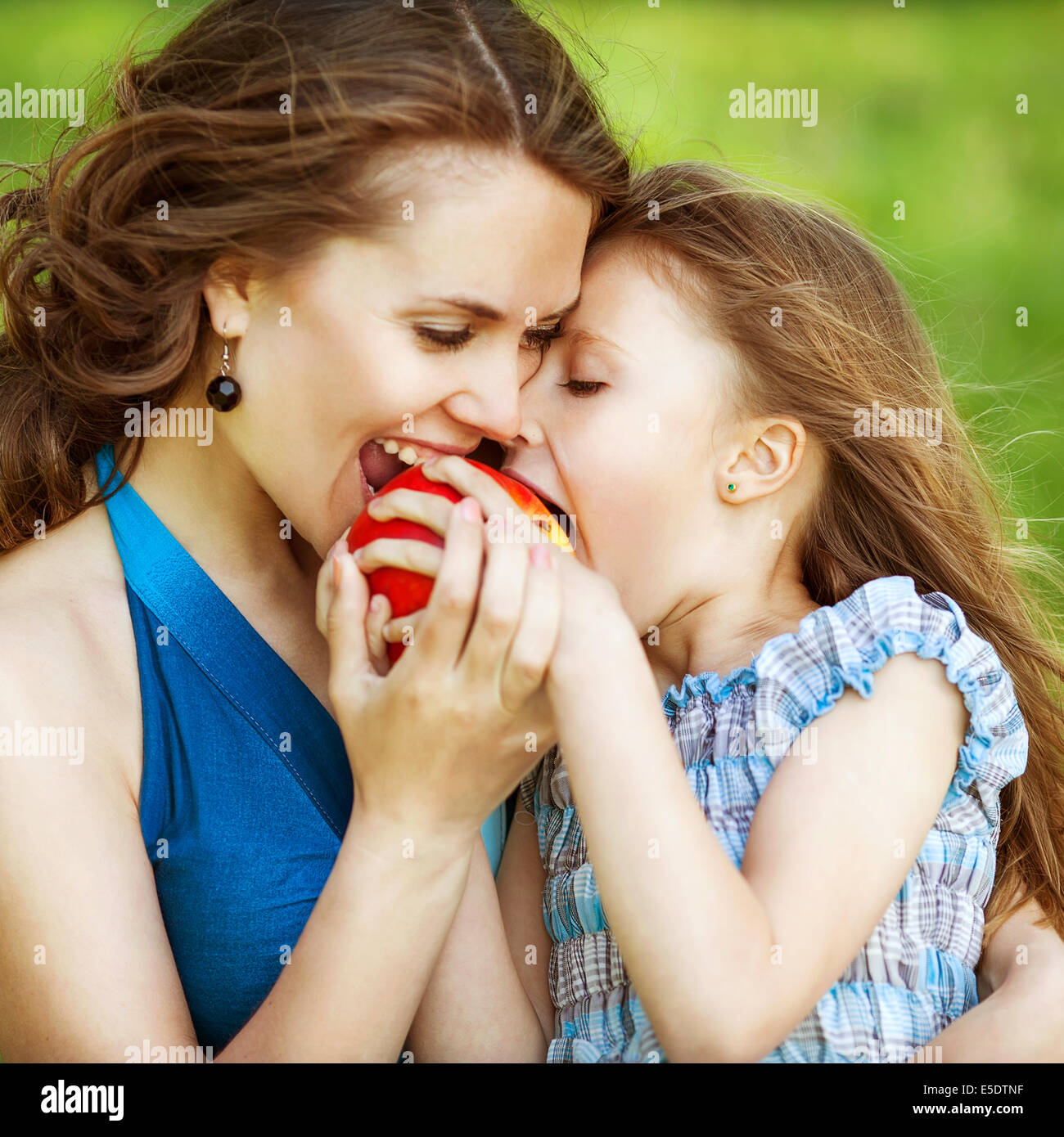 Mother and her child enjoy the early spring, eating apple, happy Stock ...