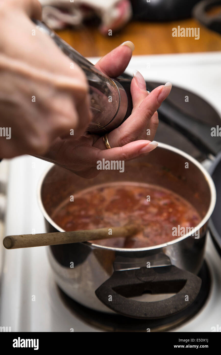 Woman cooking and adding spice to food in a home kitchen Stock Photo ...