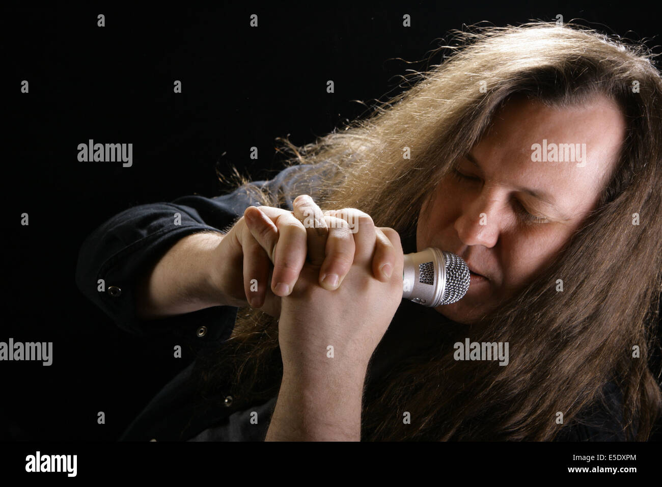 Singer with microphone over black background Stock Photo - Alamy