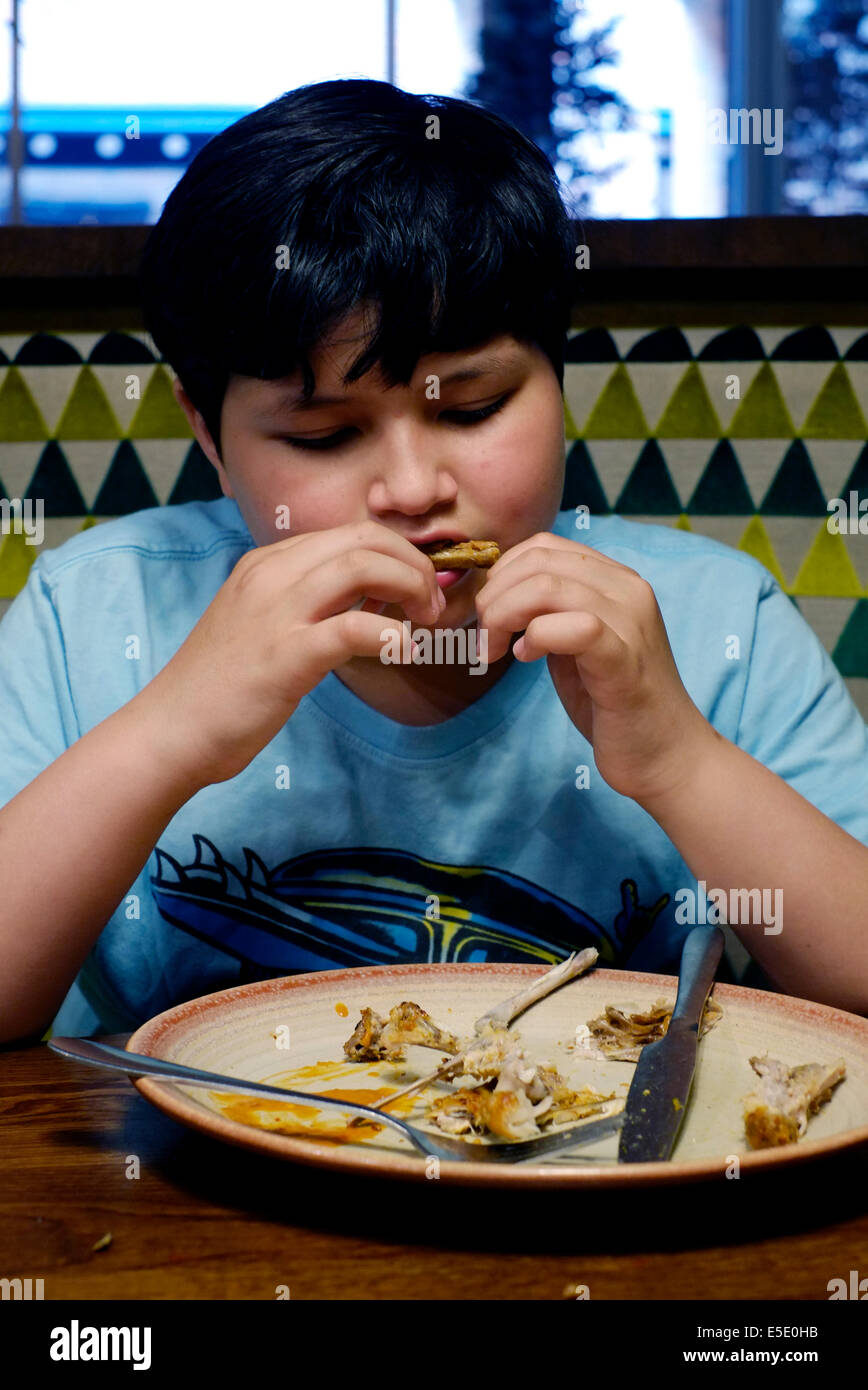 young boy enjoying a chicken meal with hot sauce he has chosen from the ...