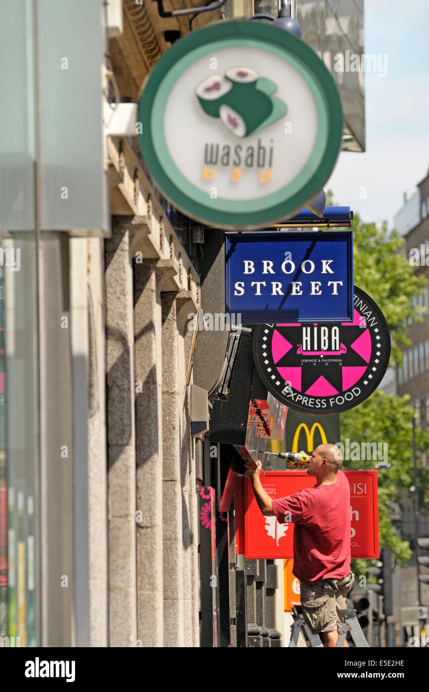 London, England, UK. Man fixing a shop sign Stock Photo - Alamy