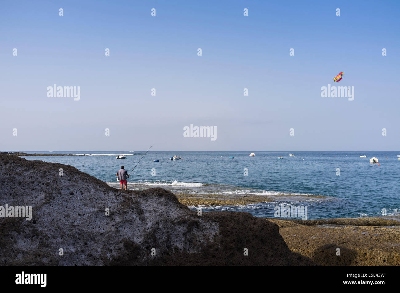 Fisherman fishing off the rocks at the coast in La Caleta, Costa Adeje ...