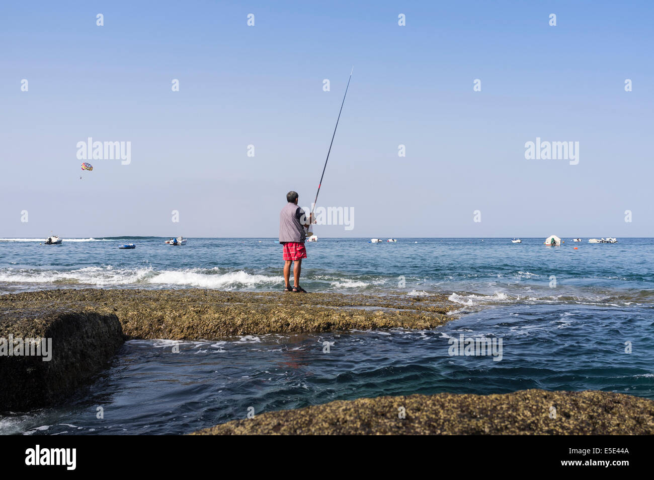 Fisherman fishing off the rocks at the coast in La Caleta, Costa Adeje ...