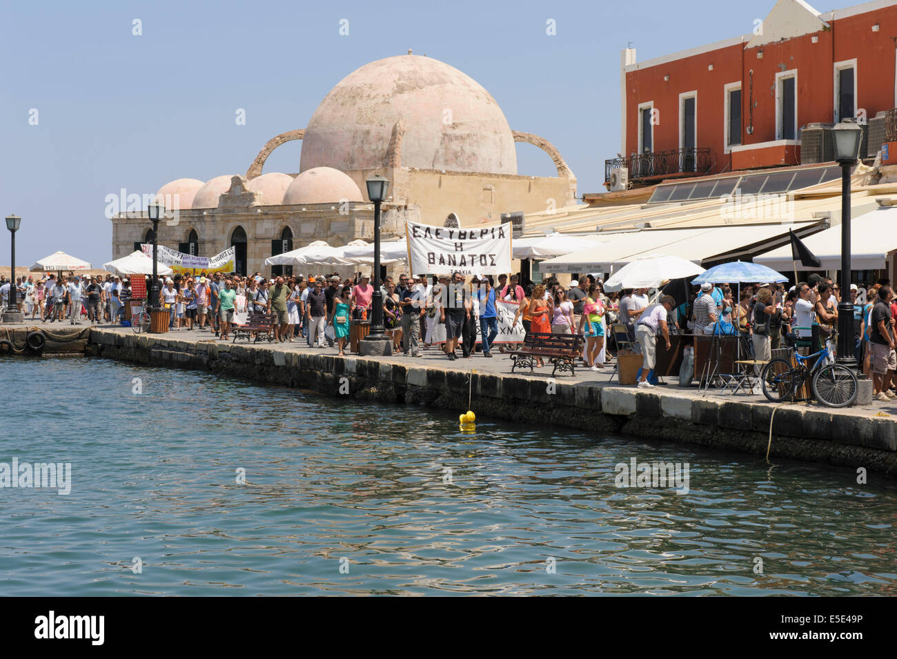 A protest march passes along the quay in Chania city centre, Crete ...
