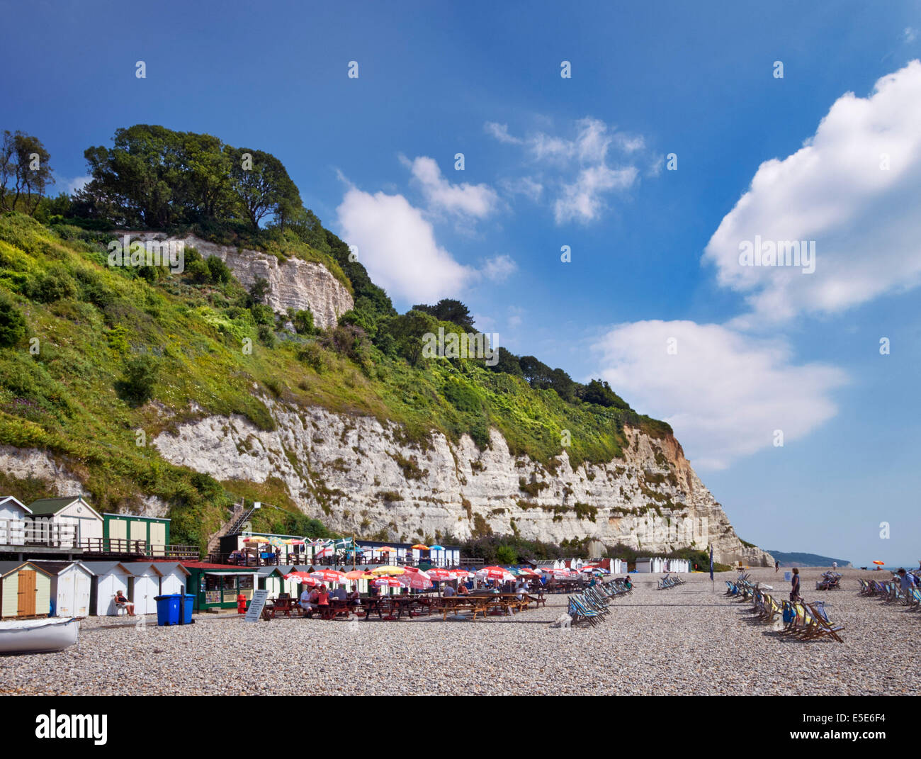 Beach huts, café and deckchairs below the cliffs at Beer, South Devon ...