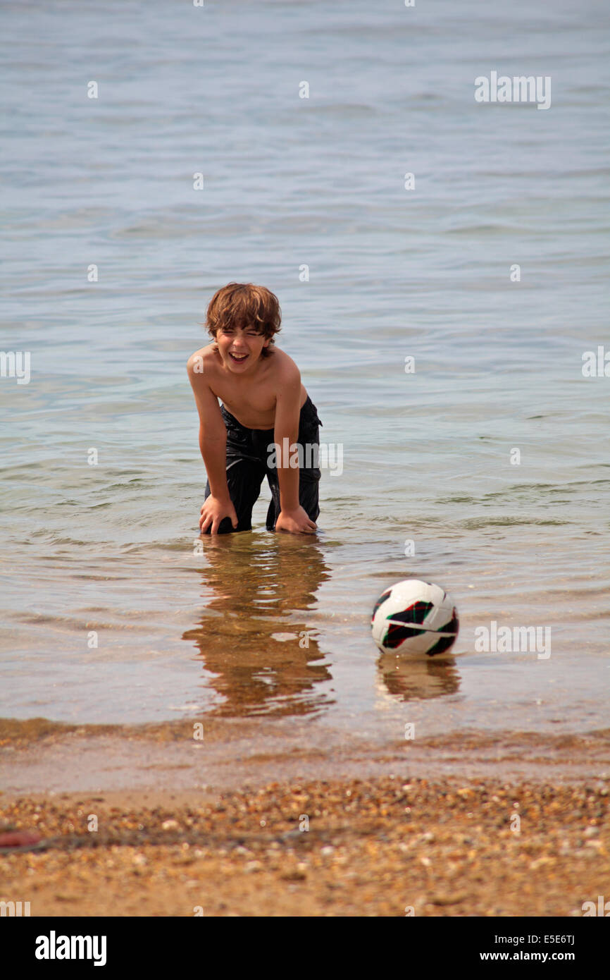 boy with football in the sea at Worbarrow Bay, Isle of Purbeck, Dorset ...