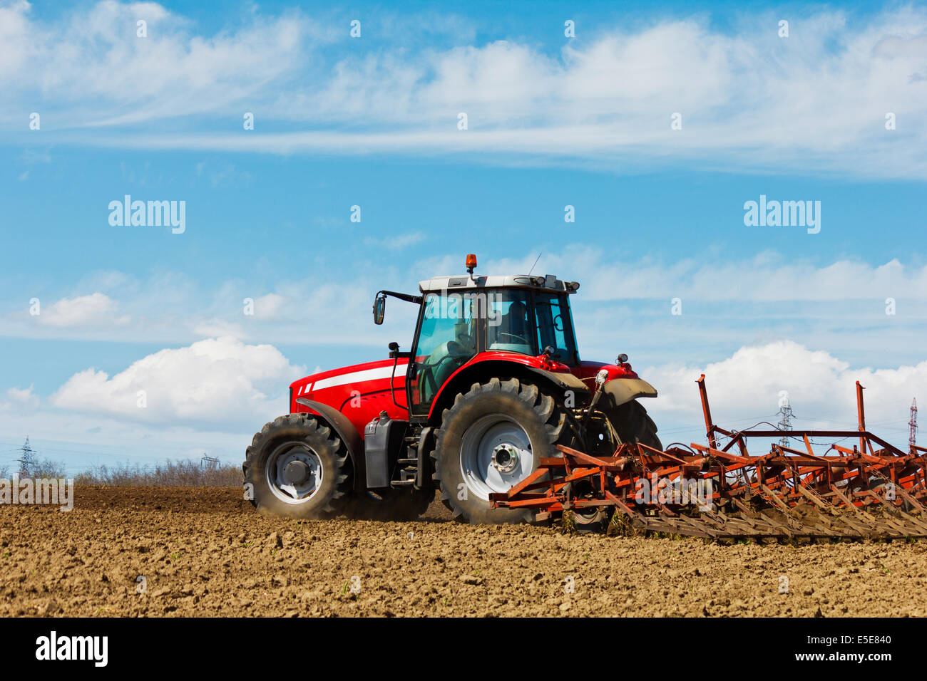 Farmer plowing the field. Cultivating tractor in the field. Red farm ...