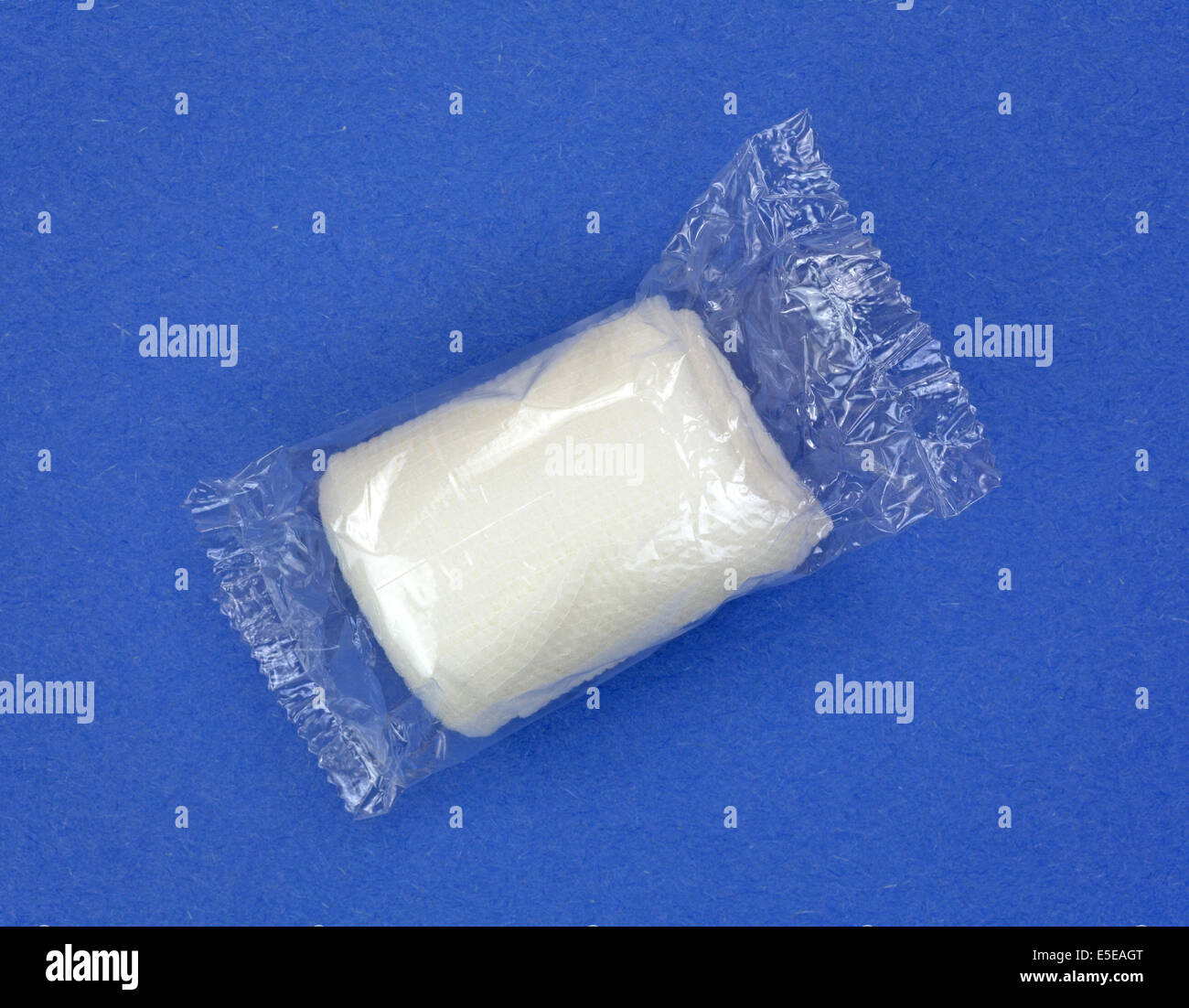 A first aid roll of gauze in a sanitized plastic wrapper atop a blue ...