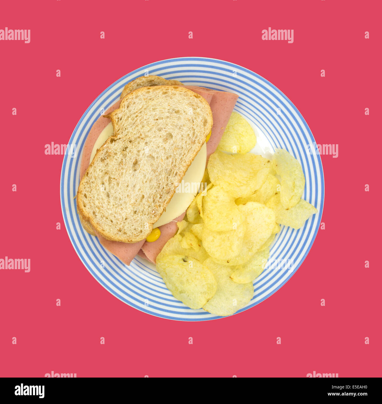 A baloney sandwich on Italian bread with chips on a blue striped plate ...