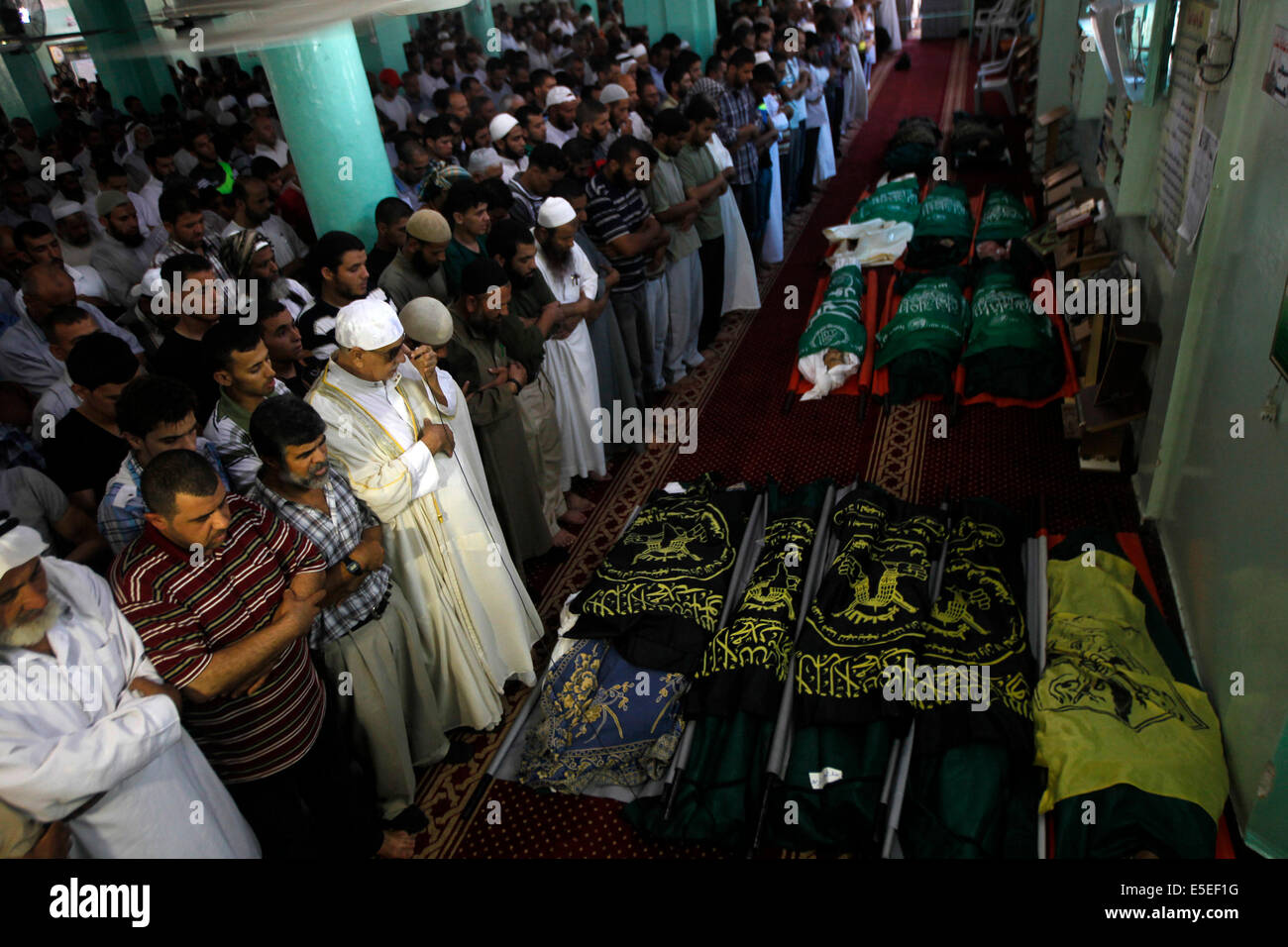 Palestinian mourners pray around the bodies of fifteen members of the ...