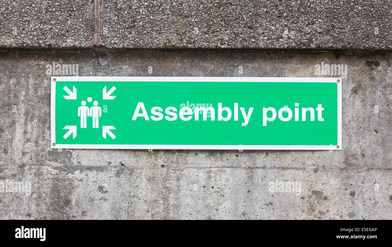 Green plastic 'assembly point' sign, isolated on concrete wall Stock ...