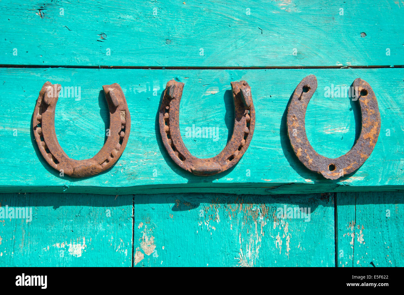 three old rusty horseshoe on old wooden door - luck symbol Stock Photo ...